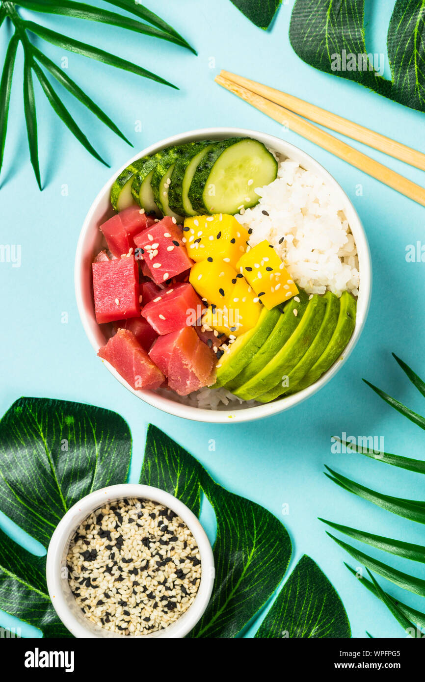 Tuna poke bowl with rice, avocado, mango and cucumber on blue Stock ...