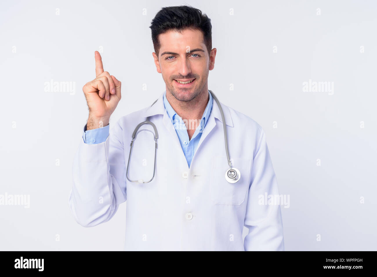 Portrait of happy young handsome man doctor pointing up Stock Photo - Alamy