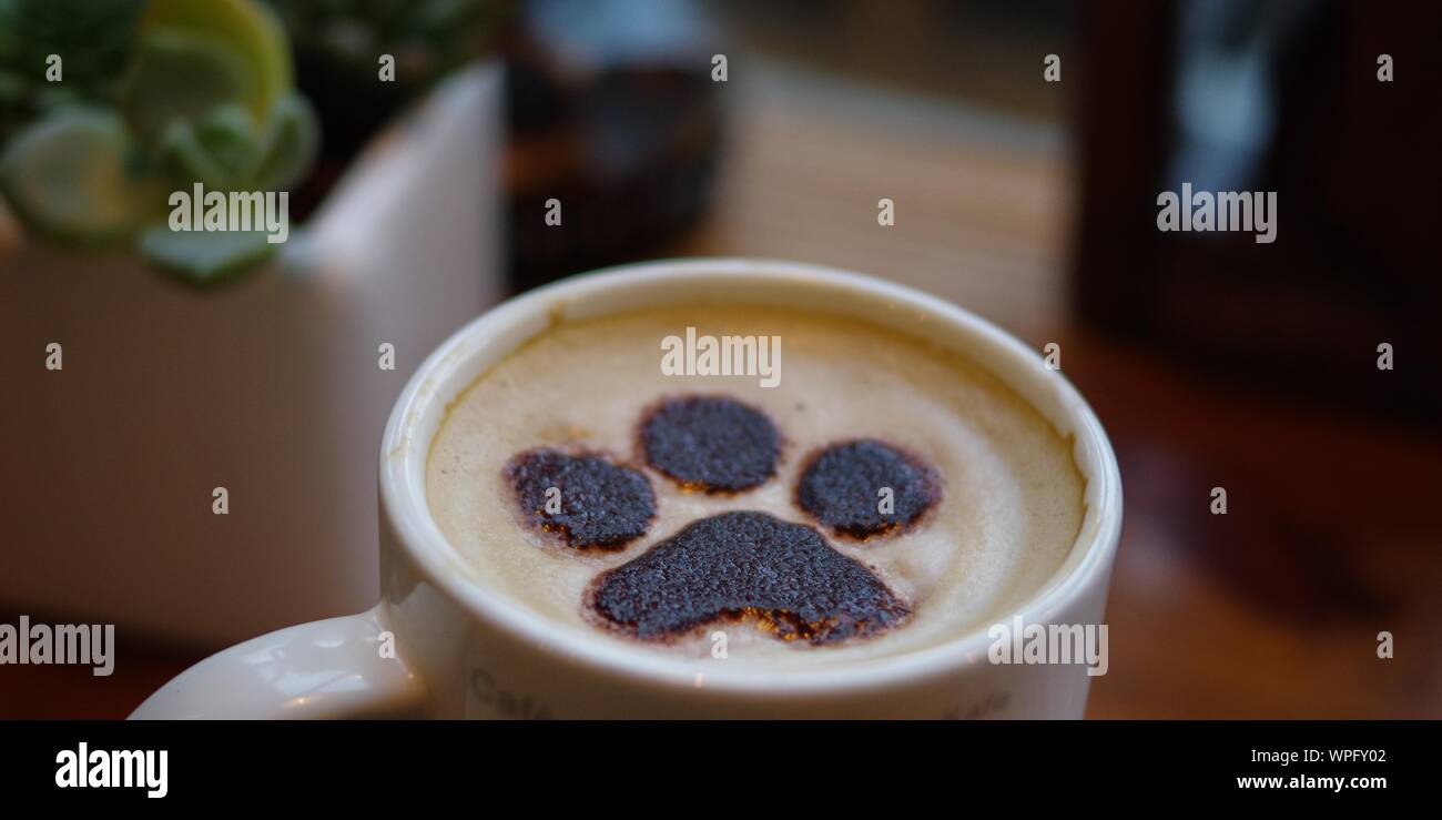 Cat paw pattern latte art coffee in white mug on wood table with ...