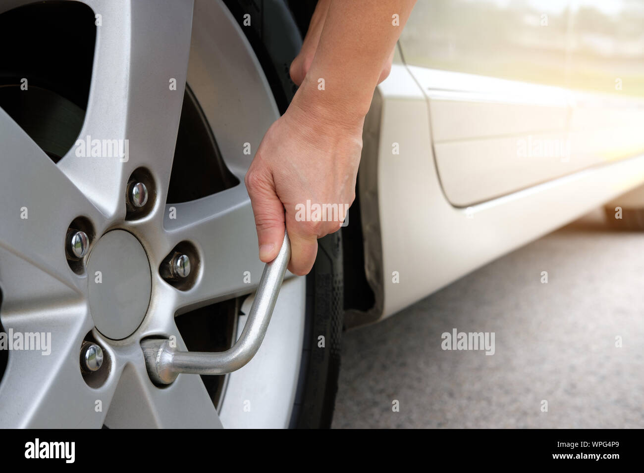 Hand changing tire with car wrench Stock Photo - Alamy