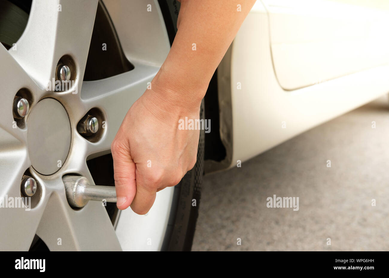 Hand changing tire with car wrench Stock Photo - Alamy