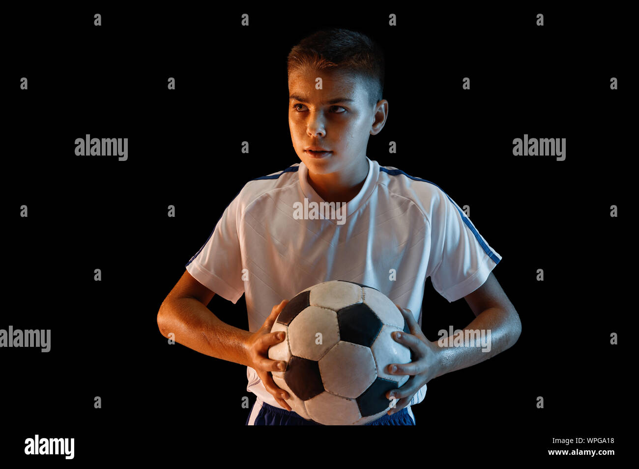 Young boy as a soccer or football player in sportwear making a feint or ...