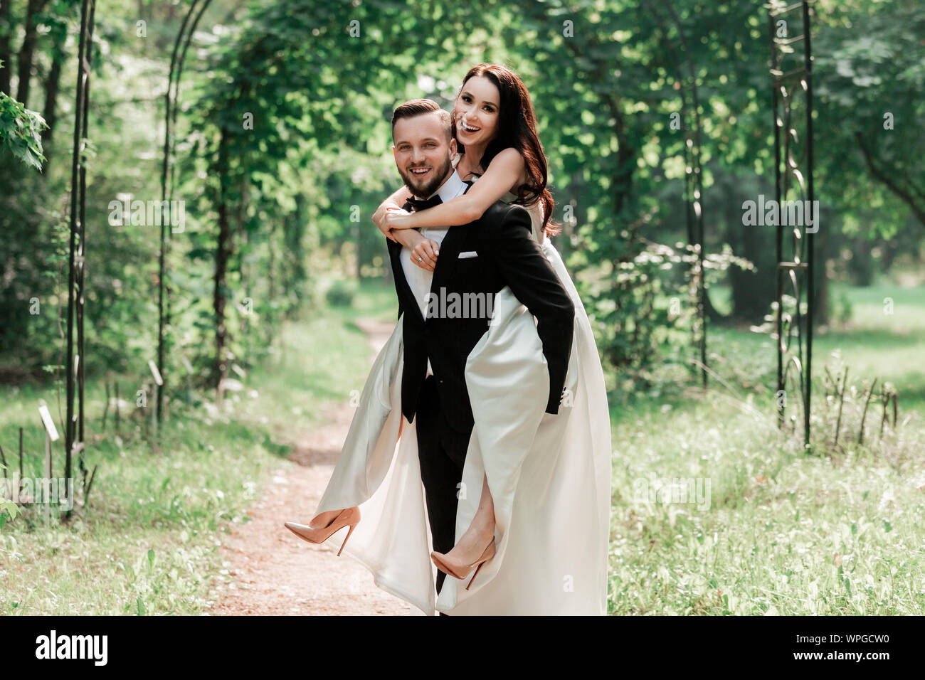 cheerful bride and groom standing under the wedding arch Stock Photo ...