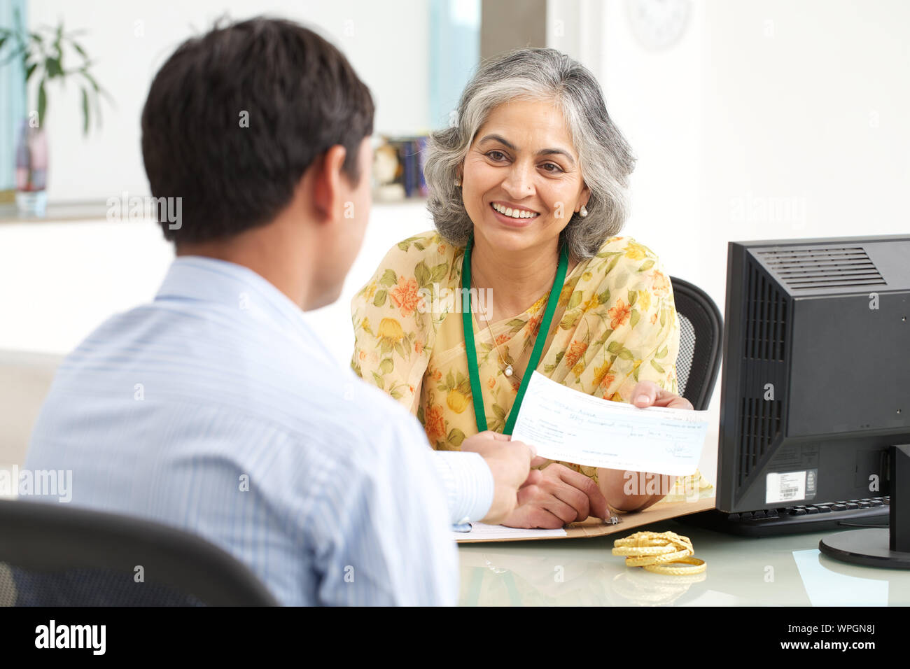 Customer receiving cheque to bank manager as gold loan Stock Photo - Alamy