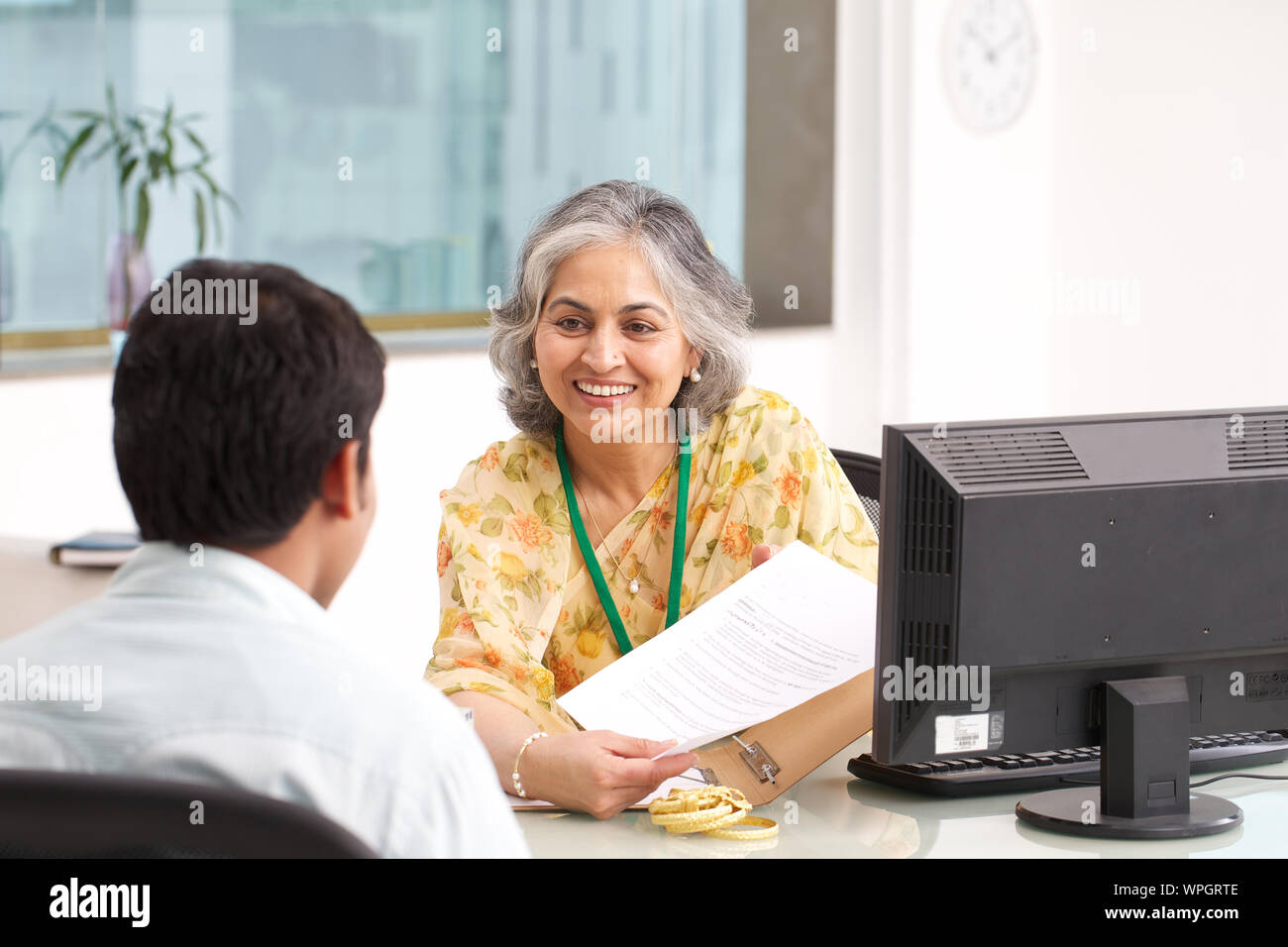 Bank manager showing the papers of gold loan to her customer Stock ...
