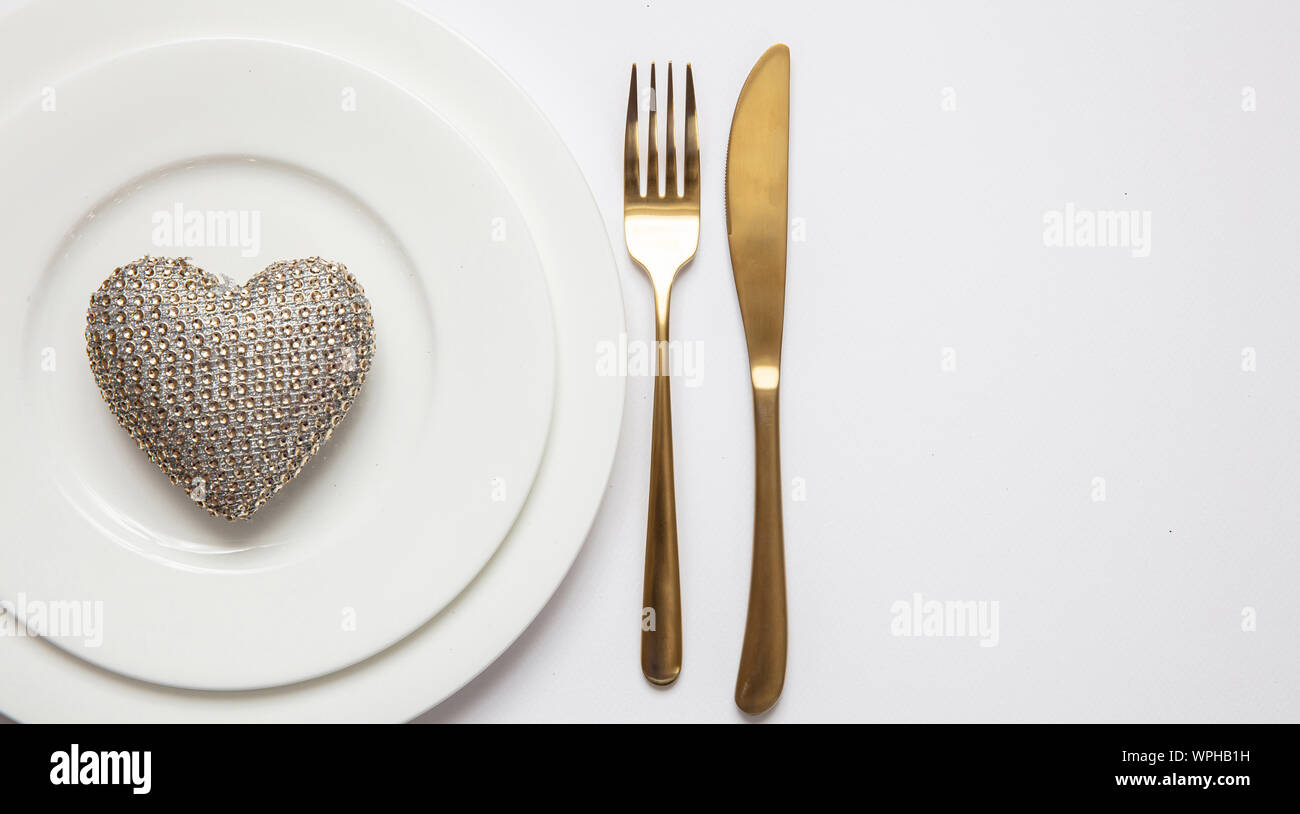 Wedding anniversary dinner table setting, Gold fork and knife on white ...