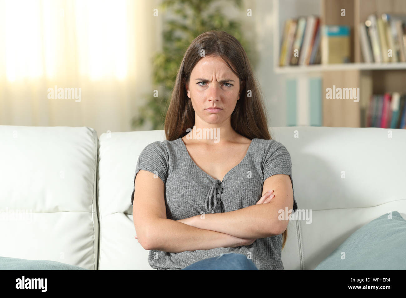 Front view portrait of an annoyed woman looking at camera sitting on a ...