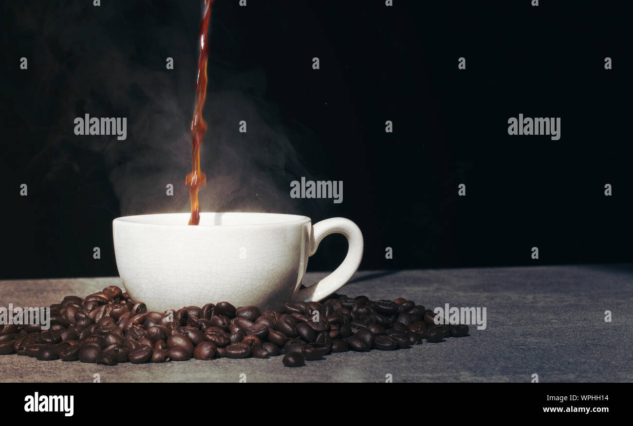 Coffee pouring to cup with coffee bean on black background Stock Photo ...