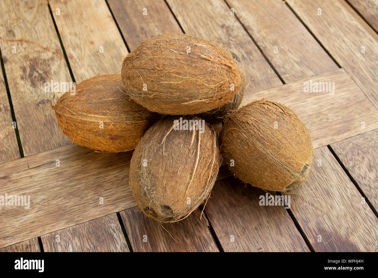 A Pile of whole coconuts on the wood table. Vegetarian and healthy food ...