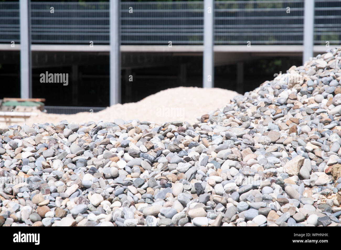 close-up of a heap of pebbles at construction site with facade of ...