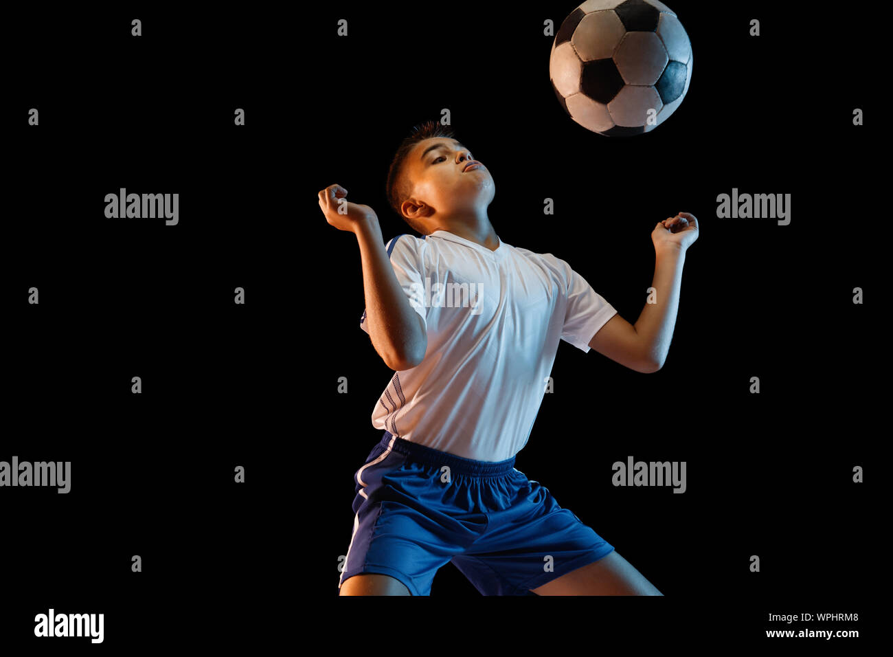 Young boy as a soccer or football player in sportwear making a feint or ...