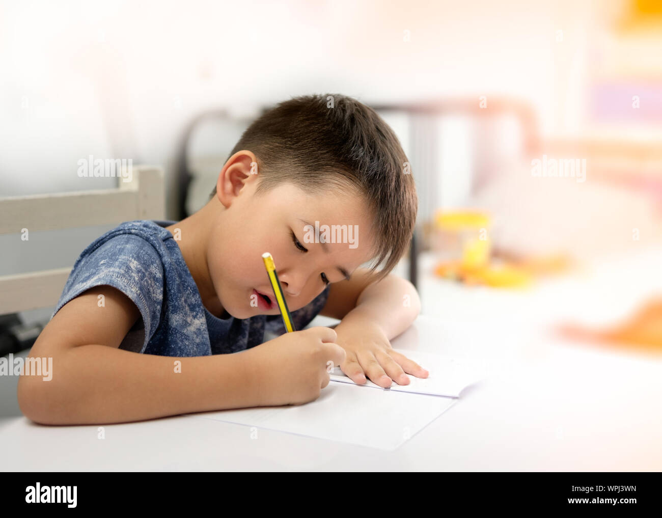 Asian boy is doing homework and writing with the intended face ...