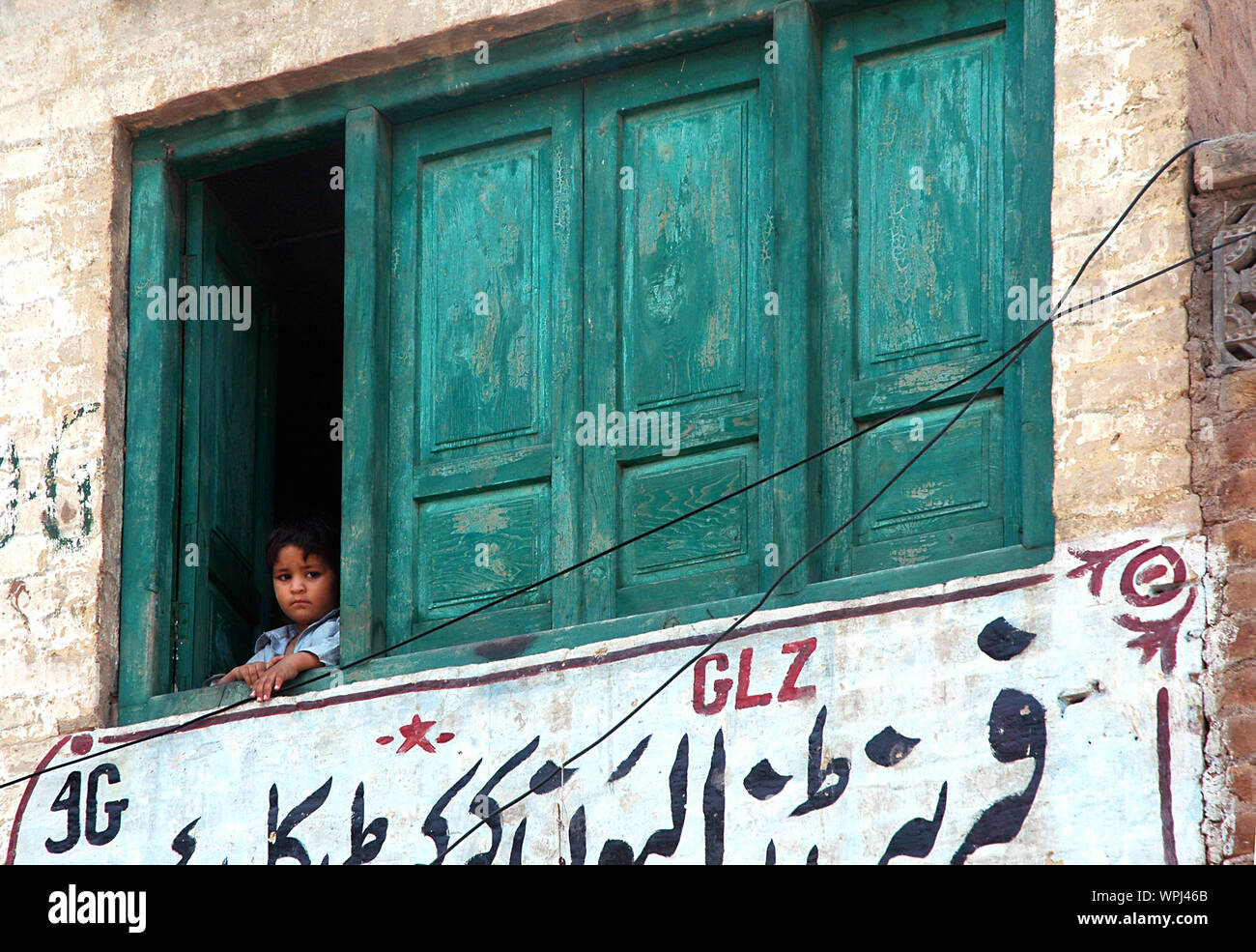 Young Pakistani boy looking out of a window in Peshawar. Small boy ...