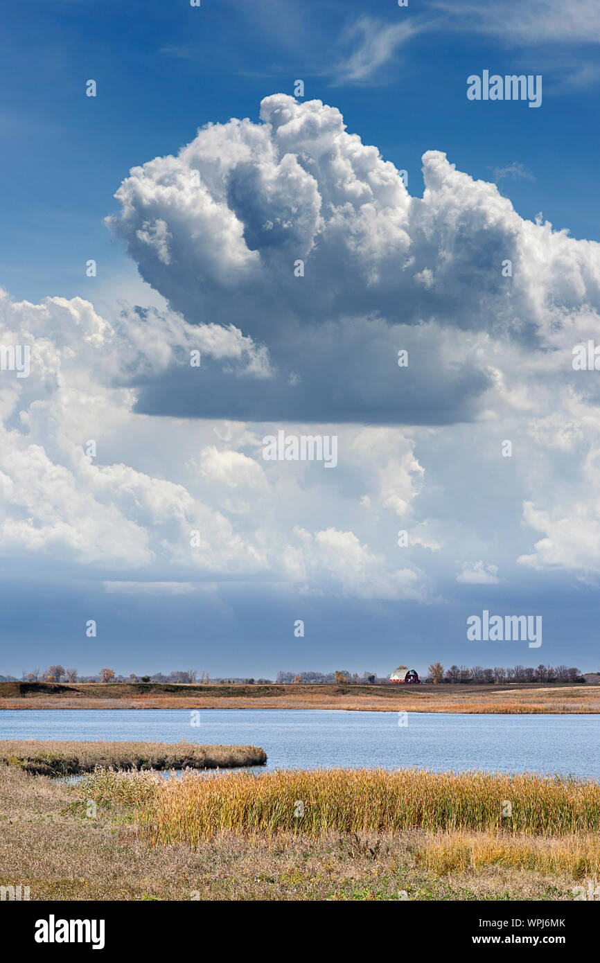 fall prairie landscape with body of water in forground and distant barn ...