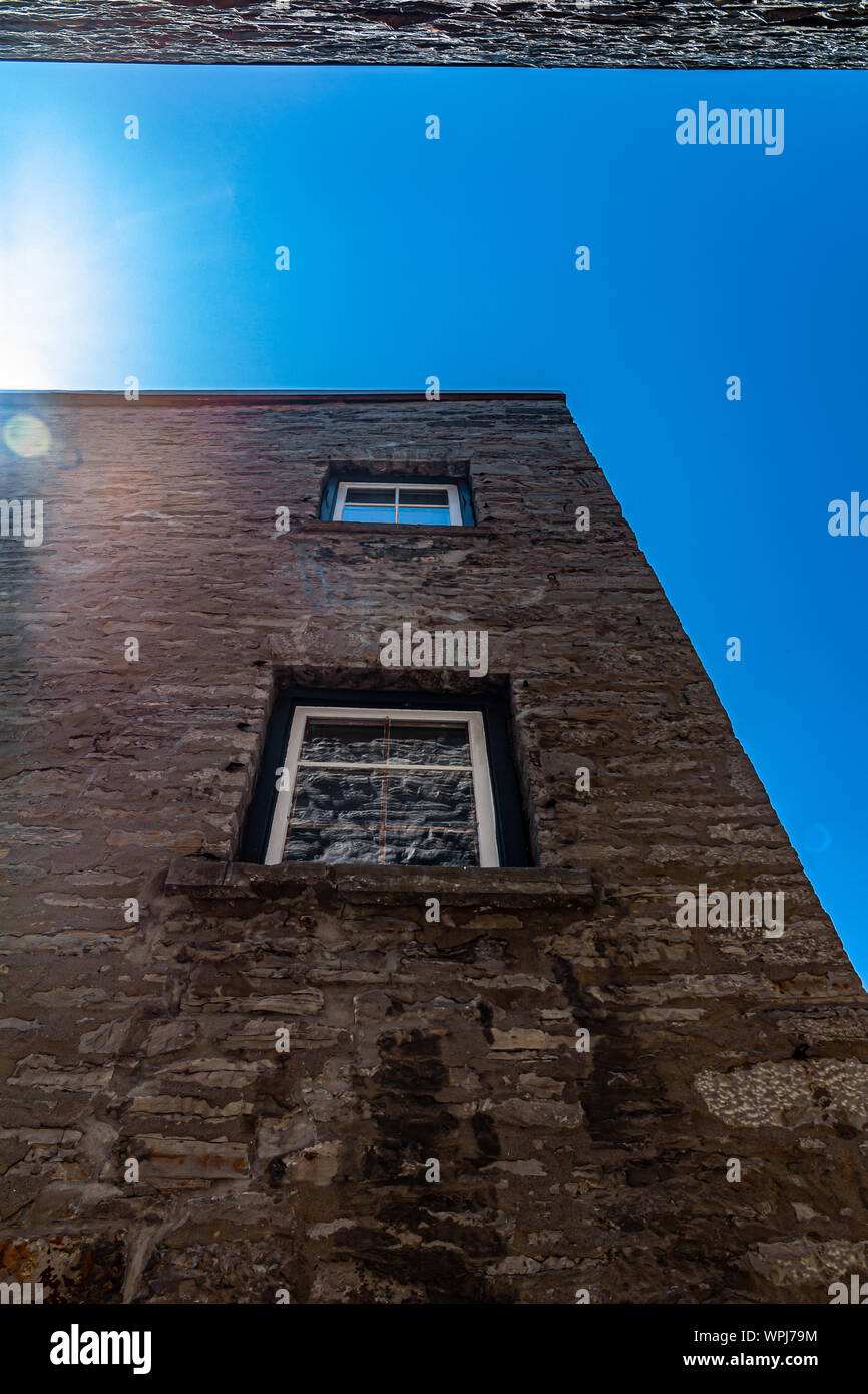 In an alleyway, the view points upwards to see the corner of a stone ...