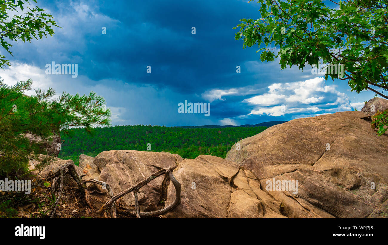A view off the edge of a cliff shows a storm forming with rain in the ...