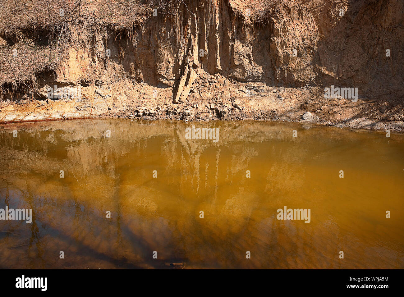 Rust color water caused by eroding sand bank. Sun shiny day with no sky ...