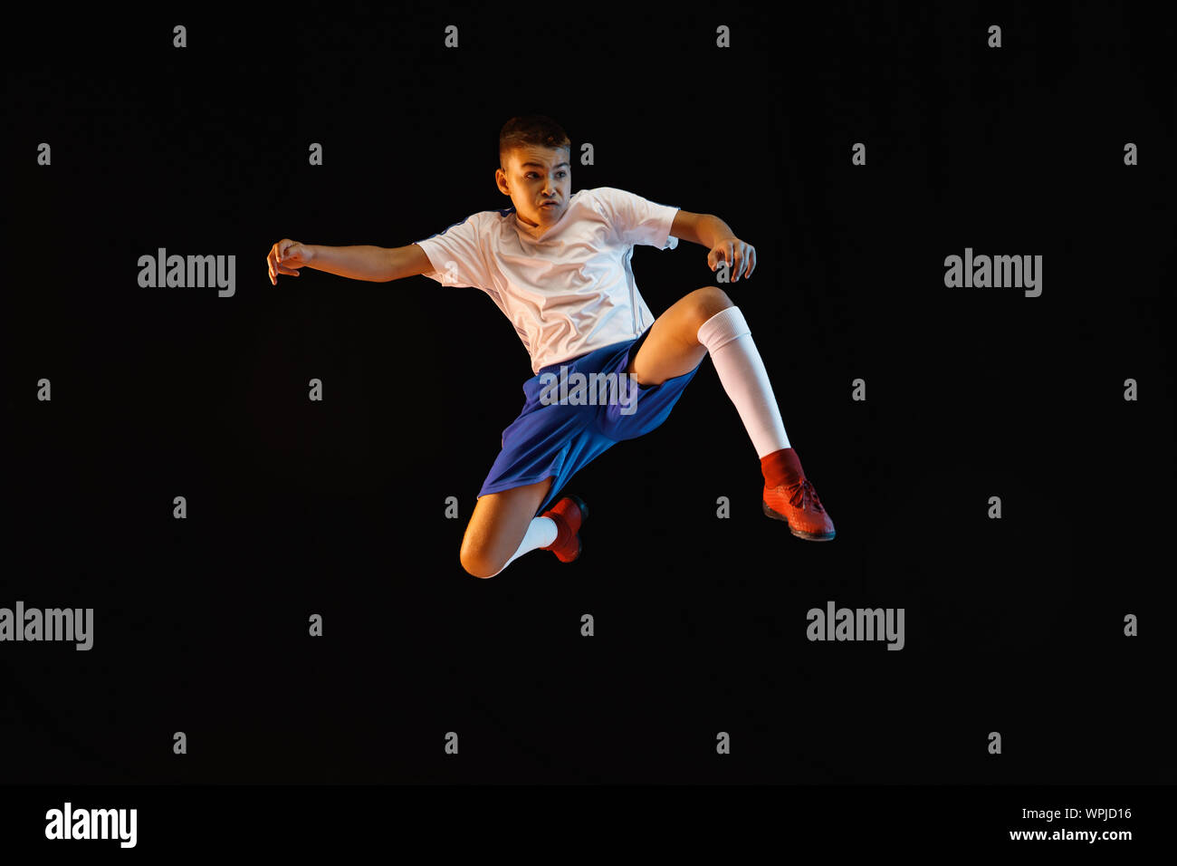 Young boy as a soccer or football player in sportwear making a feint or ...