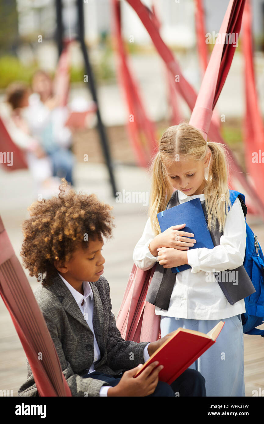 Two school classmates reading book and working together in team while ...