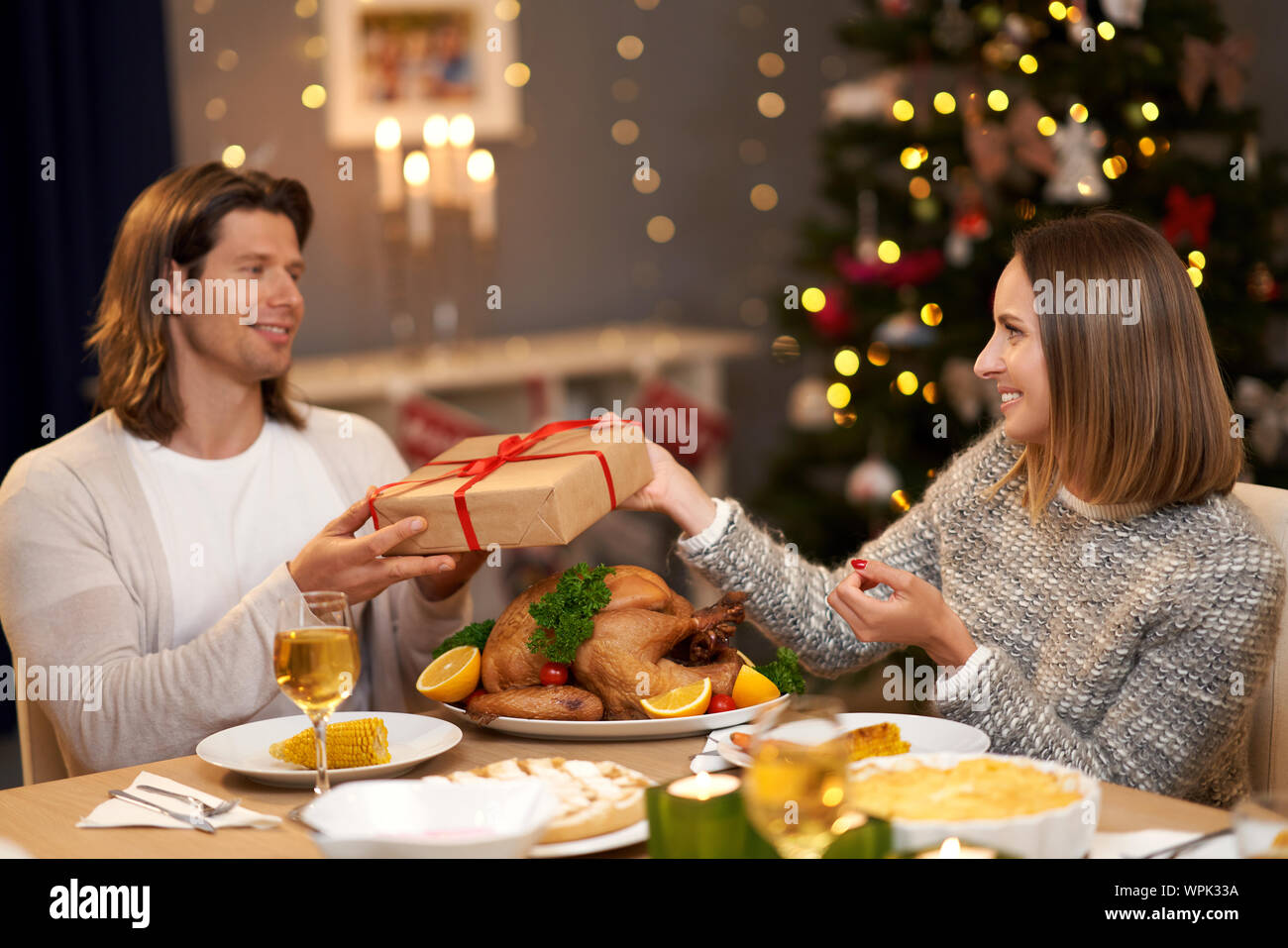 Beautiful couple sharing presents during Christmas dinner Stock Photo ...