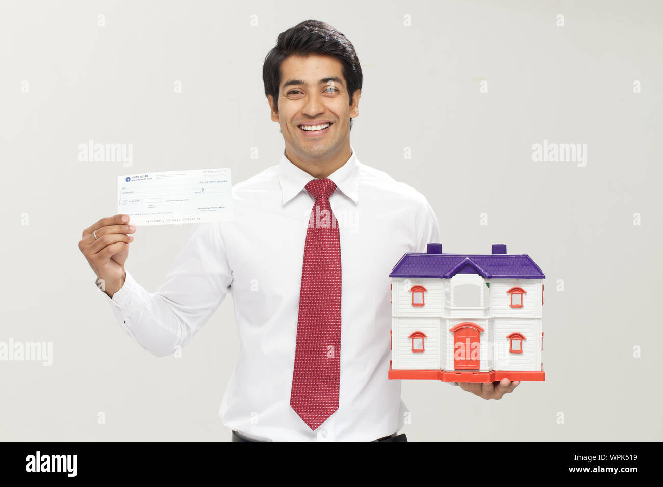Real estate agent holding a miniature house and showing a cheque Stock ...
