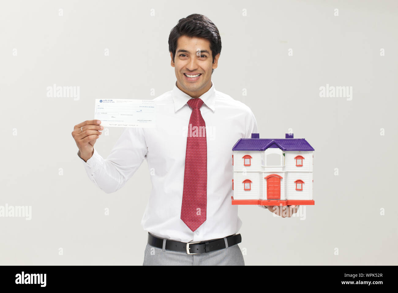 Real estate agent holding a miniature house and showing a cheque Stock ...