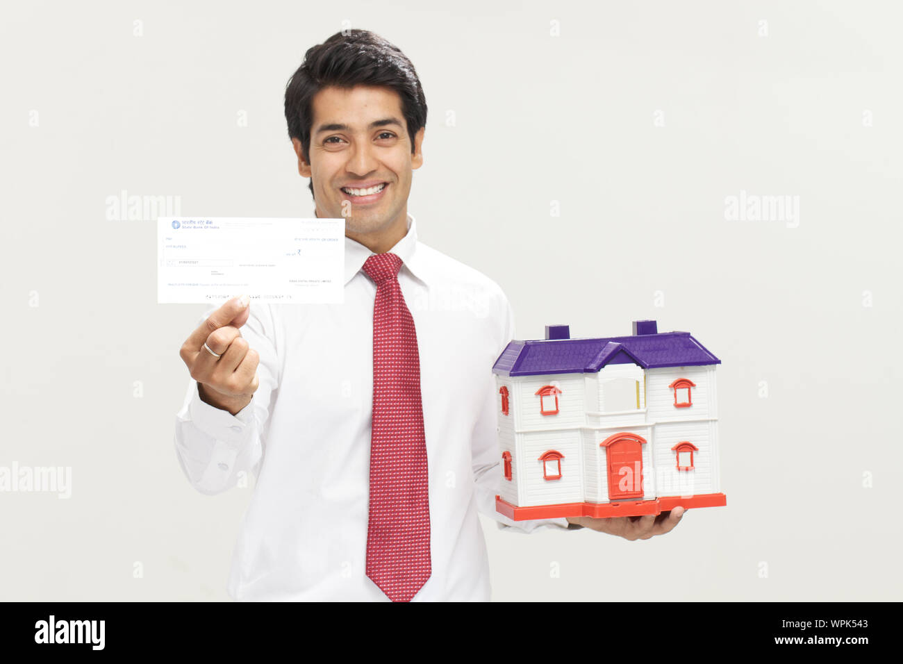 Real estate agent holding a miniature house and showing a cheque Stock ...
