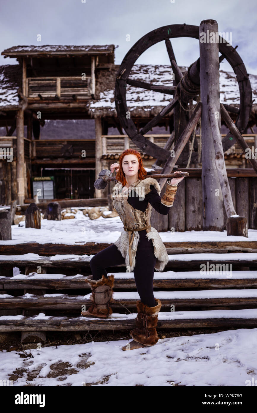 Viking woman with hammer in a traditional warrior clothes. Against the ...