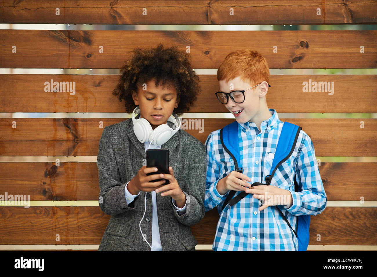 African boy using mobile phone for playing game while standing together ...