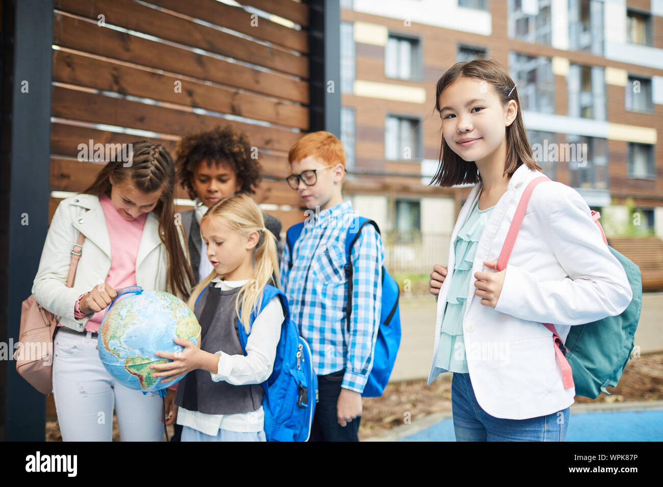 Portrait of Asian schoolgirl with backpack behind her back looking at ...