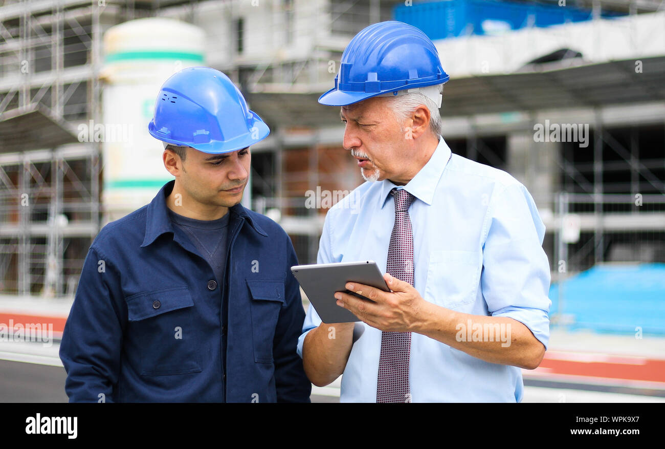 Two architect developers reviewing building plans at construction site ...
