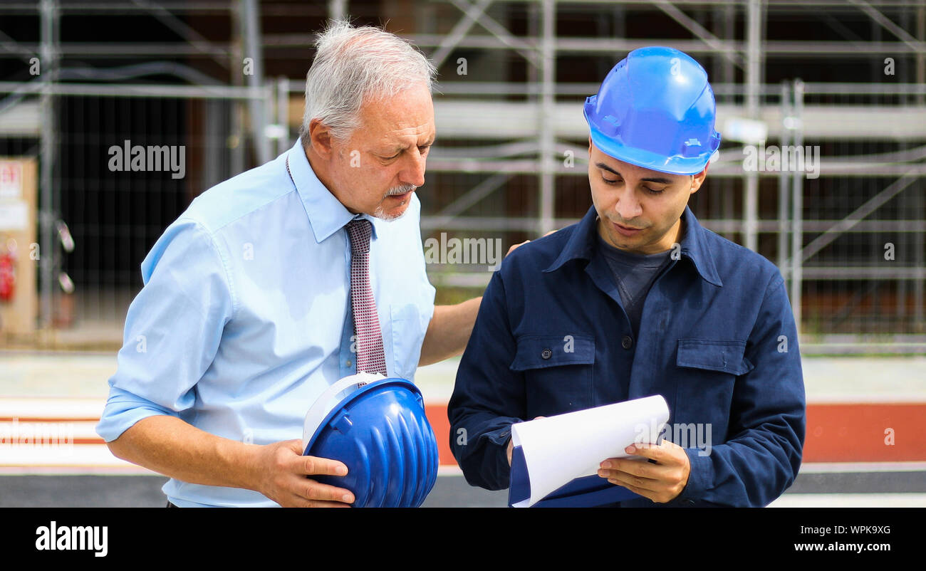 Two architect developers reviewing building plans at construction site ...