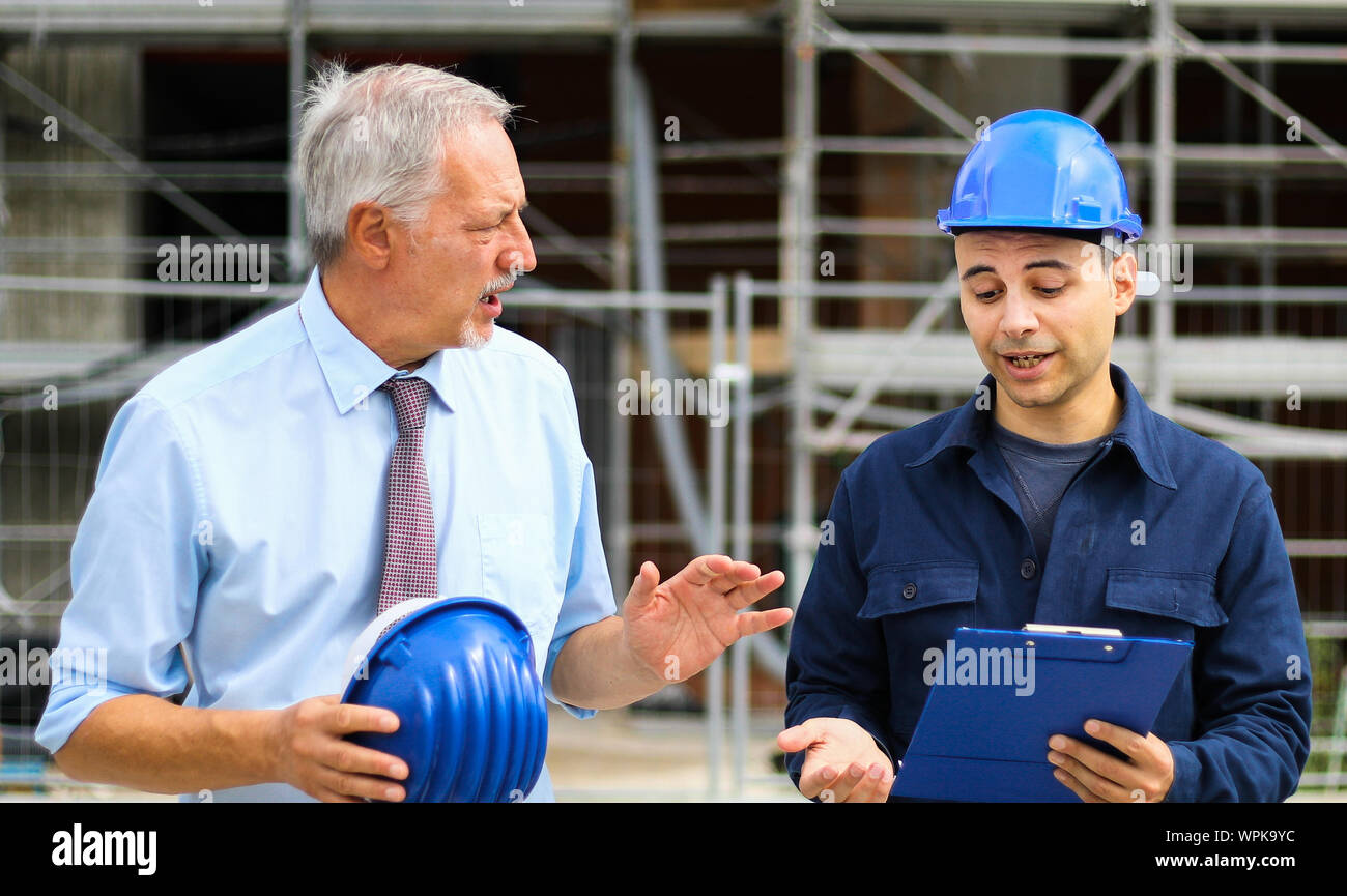Two architect developers reviewing building plans at construction site ...
