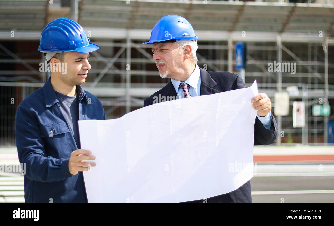 Two architect developers reviewing building plans at construction site ...