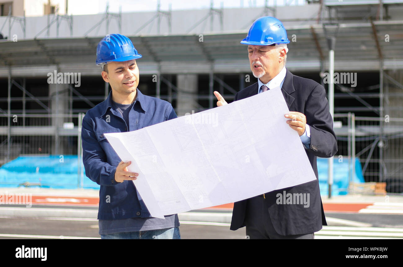 Two architect developers reviewing building plans at construction site ...