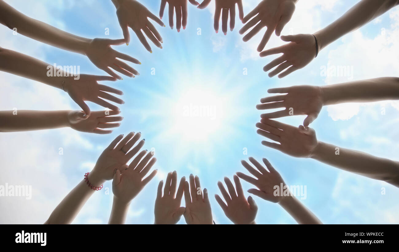 A group of young people make a circle out of their hands. Diverse ...