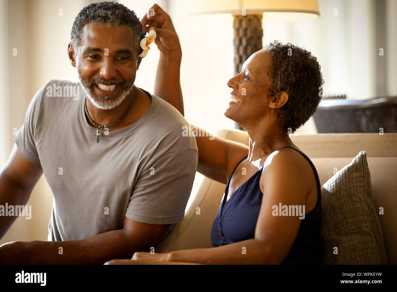 Mature woman putting flower on husband's ear Stock Photo - Alamy