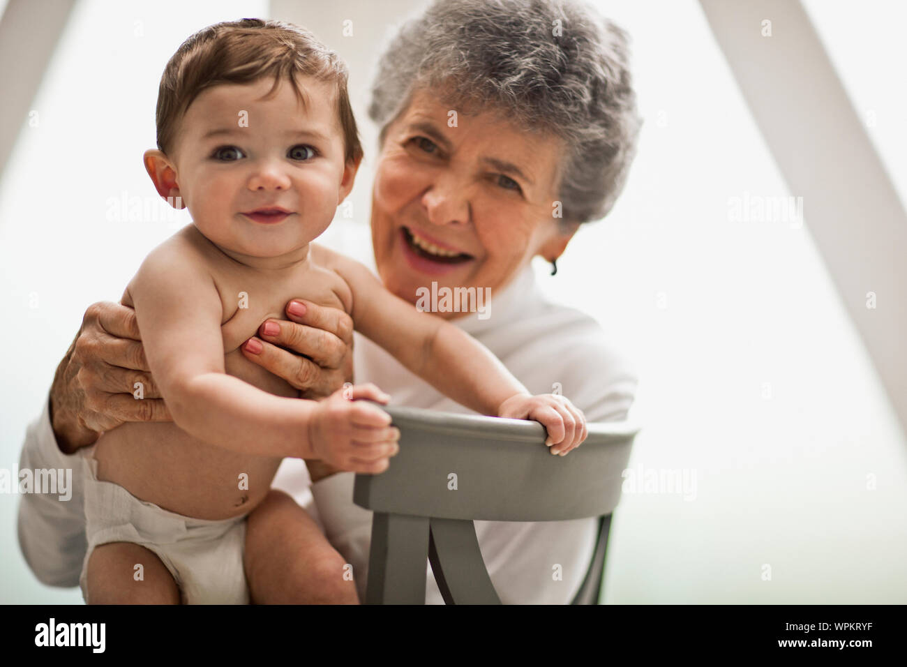 Elderly woman holding her baby grandson on the chair Stock Photo - Alamy