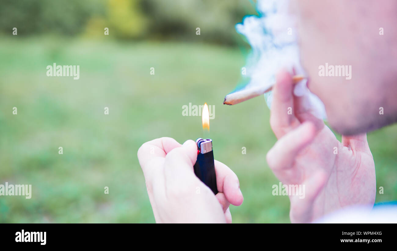 The young person smoking medical marijuana joint outdoors. The young ...