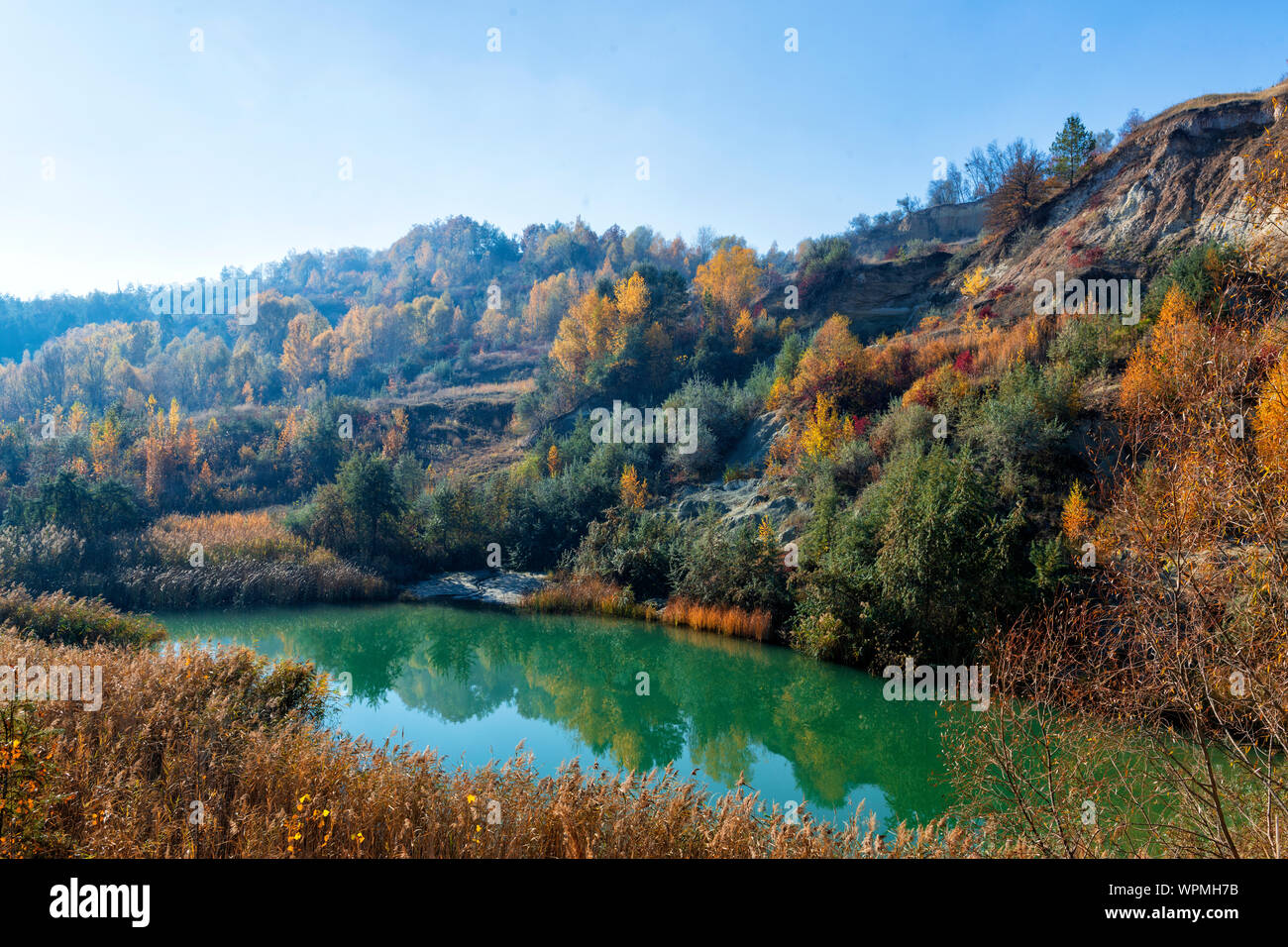 little quarry lake surrounded by earthen slopes and colorful autumn ...