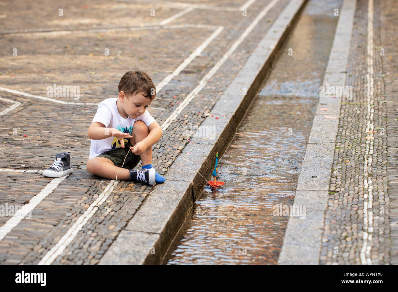 A little boy sails a toy boat in one of the famous canals of the city ...