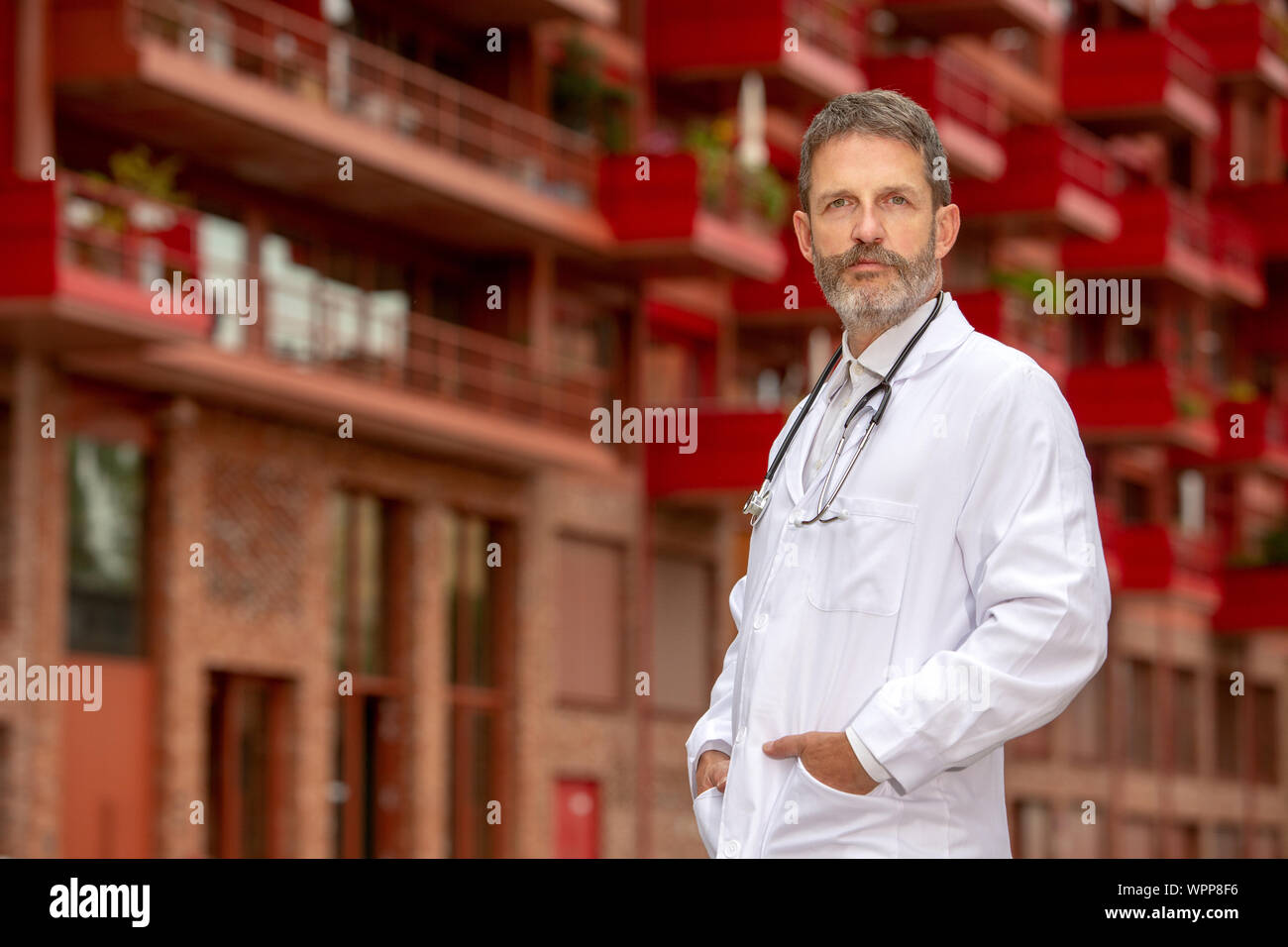 portrait of handsome bearded doctor in white coat standing outside ...