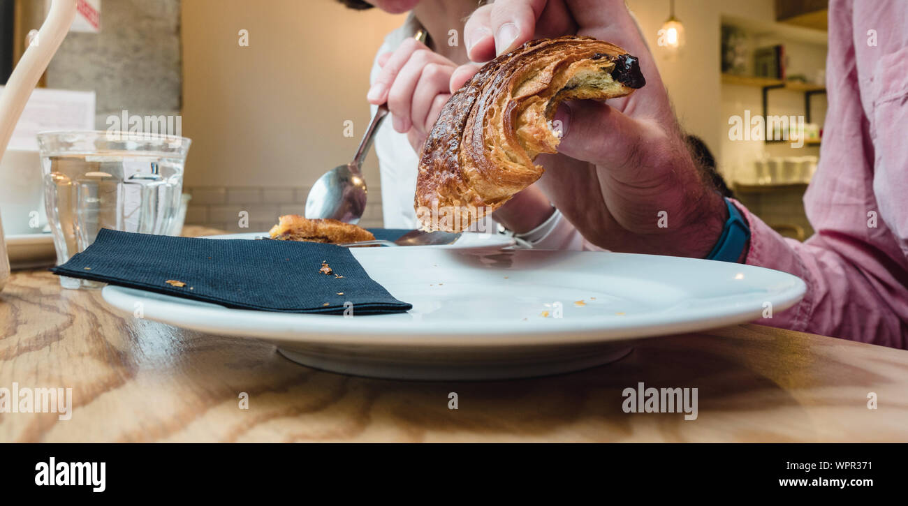 Side view of man and woman eating delicious pain au chocolat early in ...