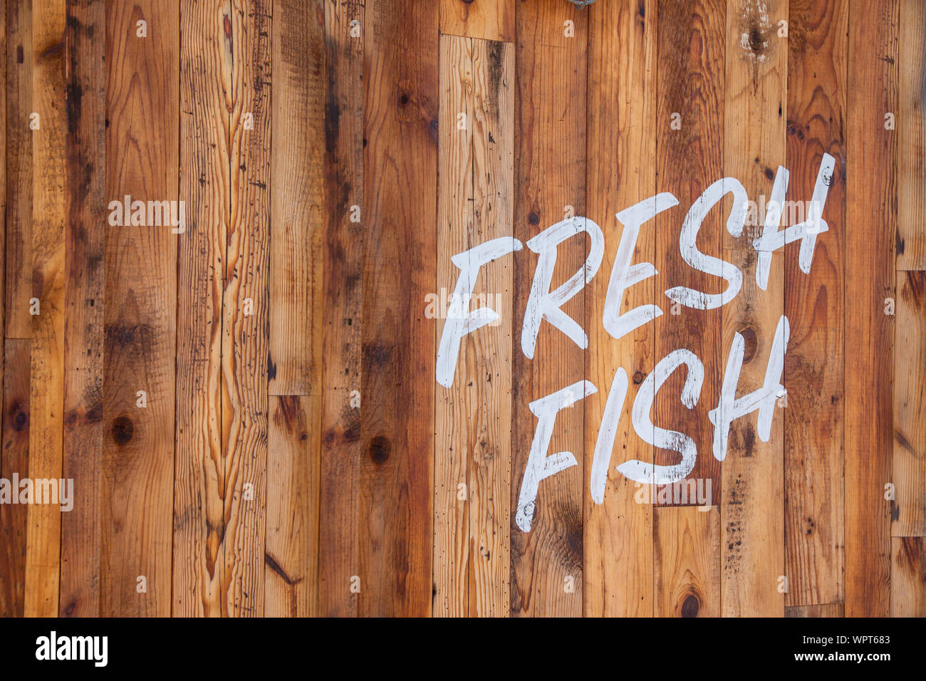 A view of a wooden wall facade and sign for fresh fish at a market ...