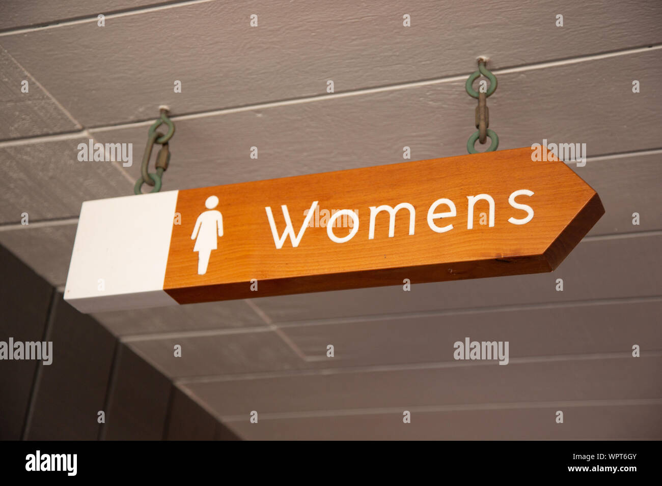 A view of a hanging wooden women's restroom sign on the ceiling Stock ...