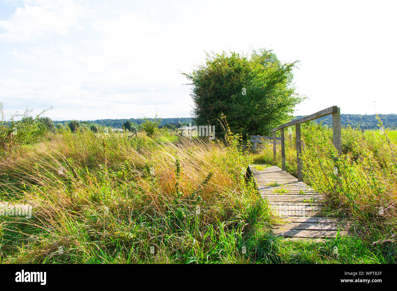 Wooden bridge over a ditch with a bench in the background in a dutch ...