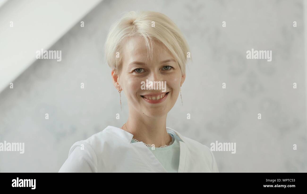 Young smiling woman - blond beautician in white lab coat Stock Photo ...