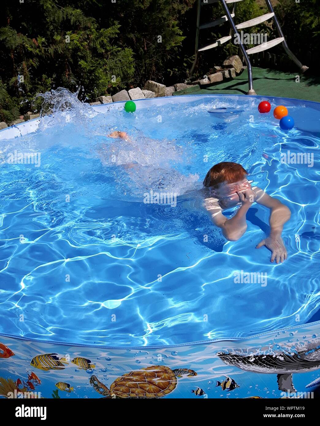 Boy splashing in swimming pool hi-res stock photography and images - Alamy