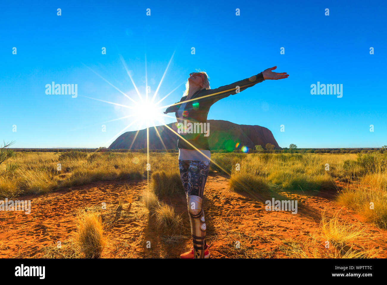 Uluru Ayers Rock silhouette at sunrise. Carefree tourist woman enjoys ...