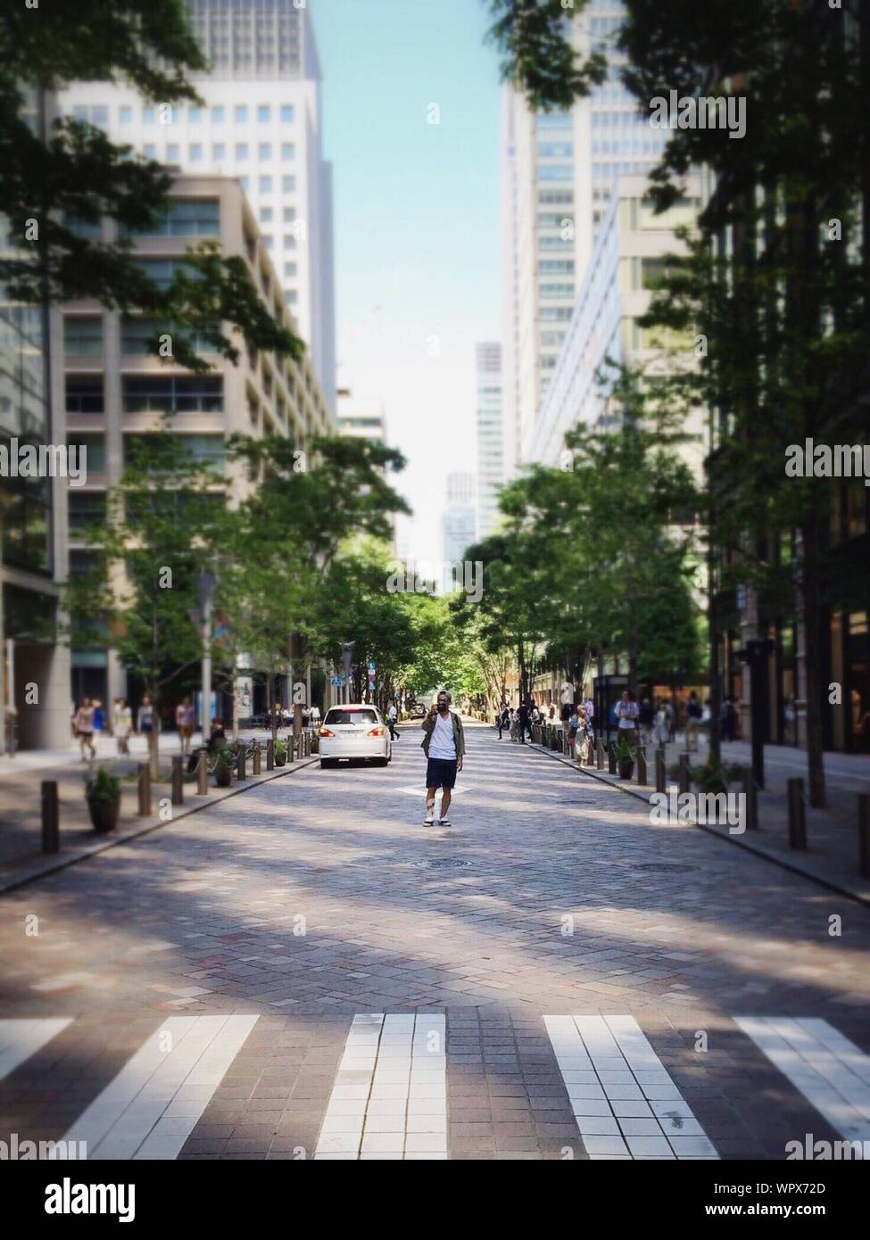 Tilt Shift Image Of Man Walking On Street Stock Photo - Alamy